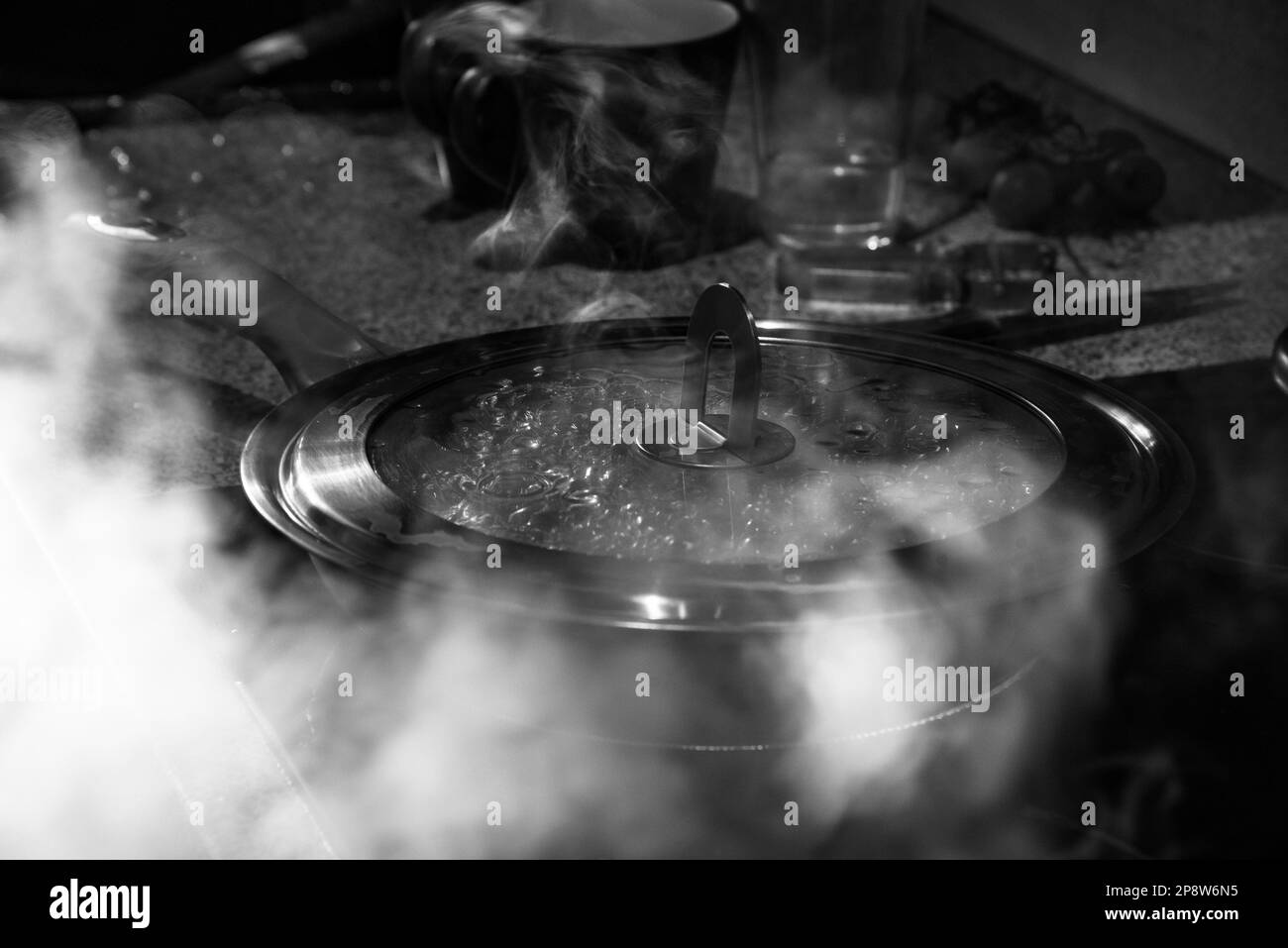 Food preparation in pan with glass cover. Steam and smoke. Black white ...