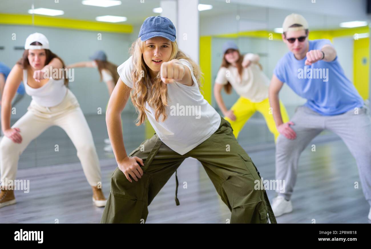 Teenage girl in cap training breakdance Toprock moves in dance hall ...