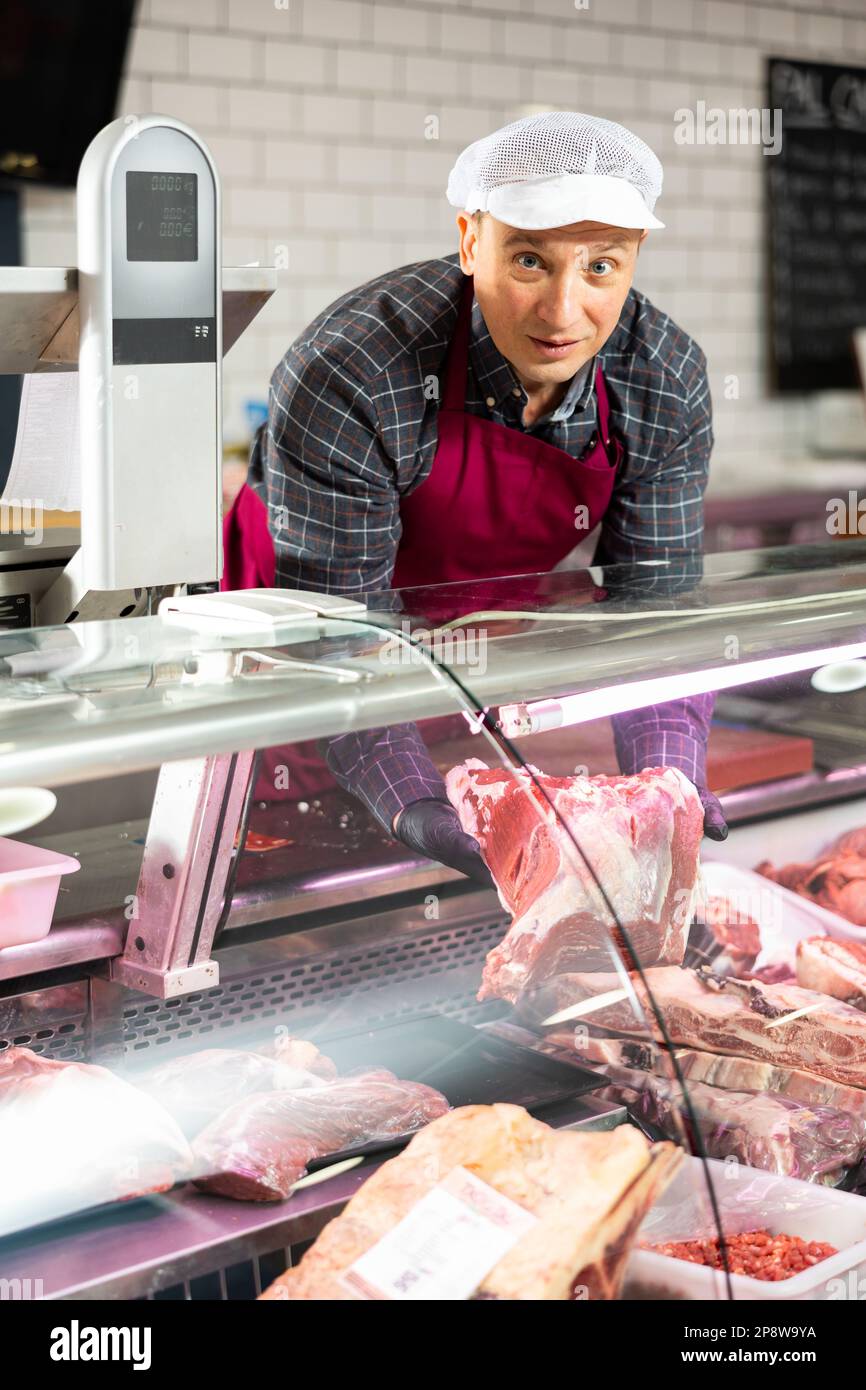 Adult man puts beef ribs in showcase Stock Photo - Alamy