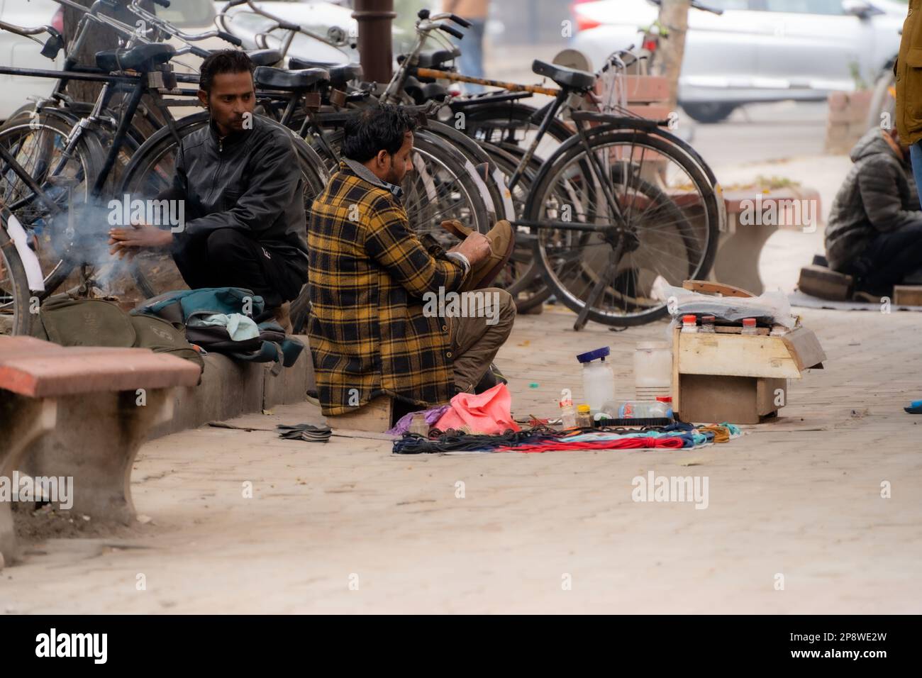 street side cobbler sitting on road and mending shoes in the winter ...