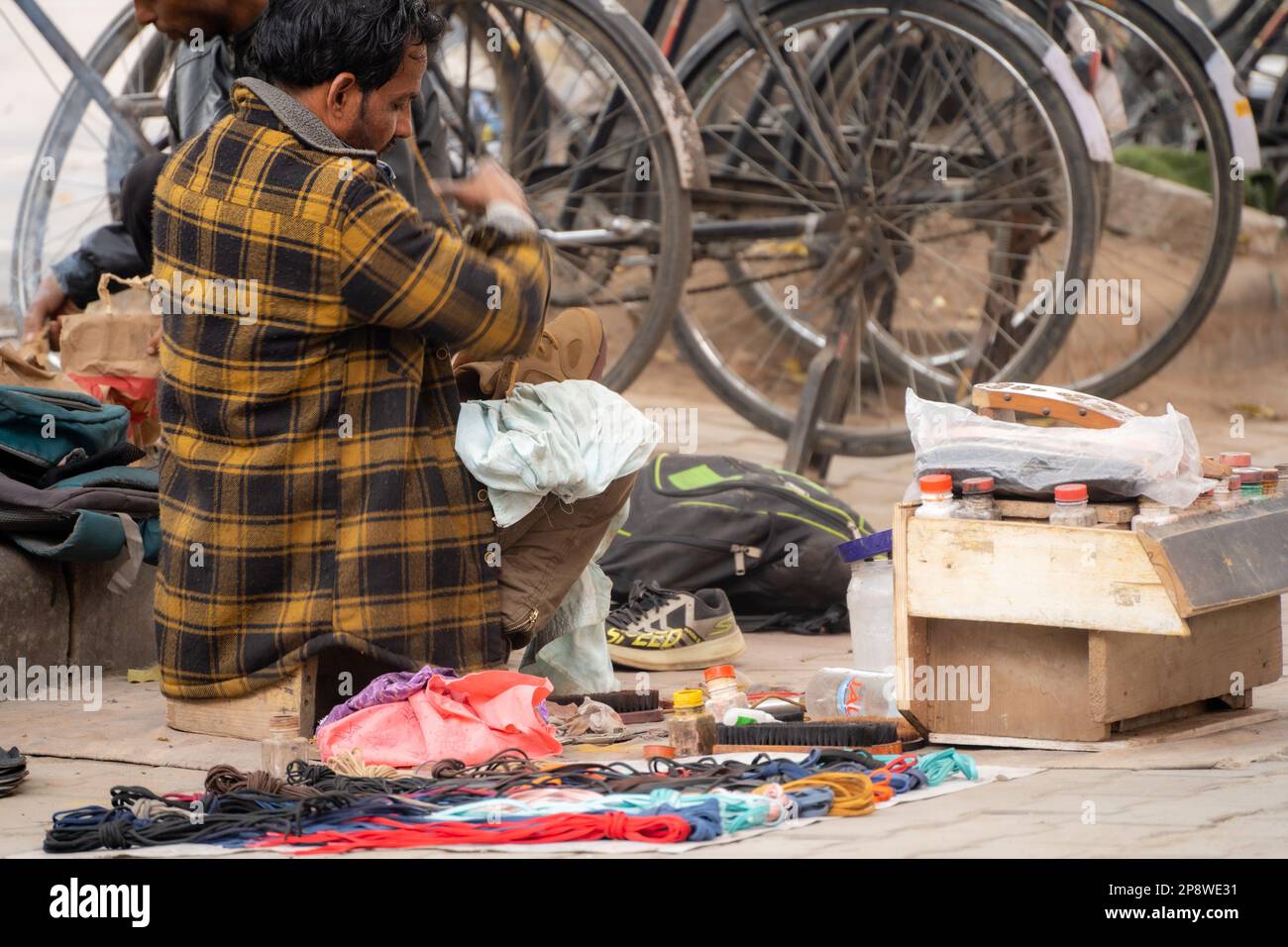 street side cobbler sitting on road and mending shoes in the winter ...