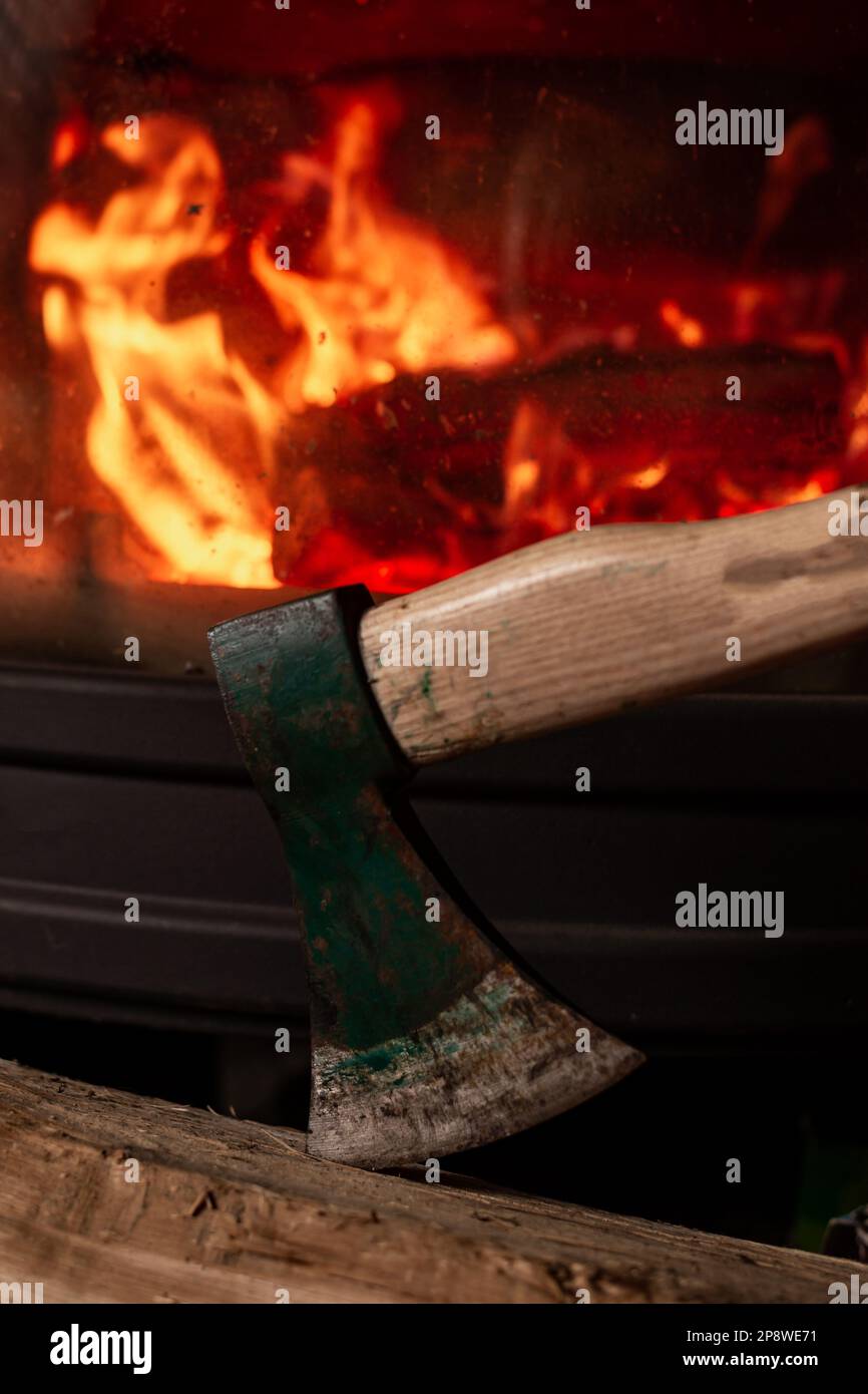 Axe with log on background of burning fireplace. Wood heating, firewood ...