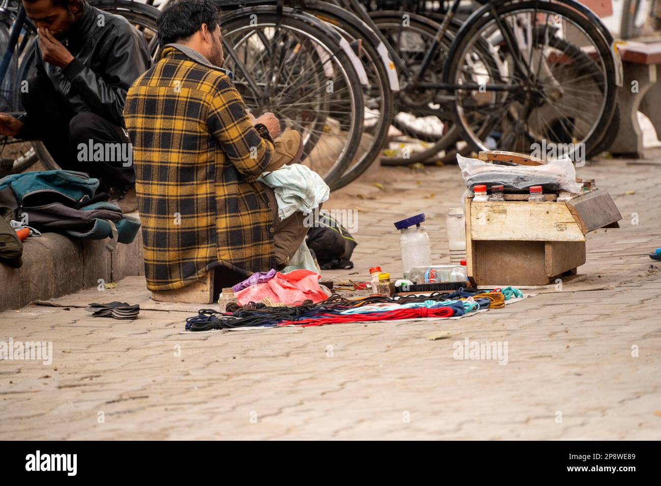 street side cobbler sitting on road and mending shoes in the winter ...