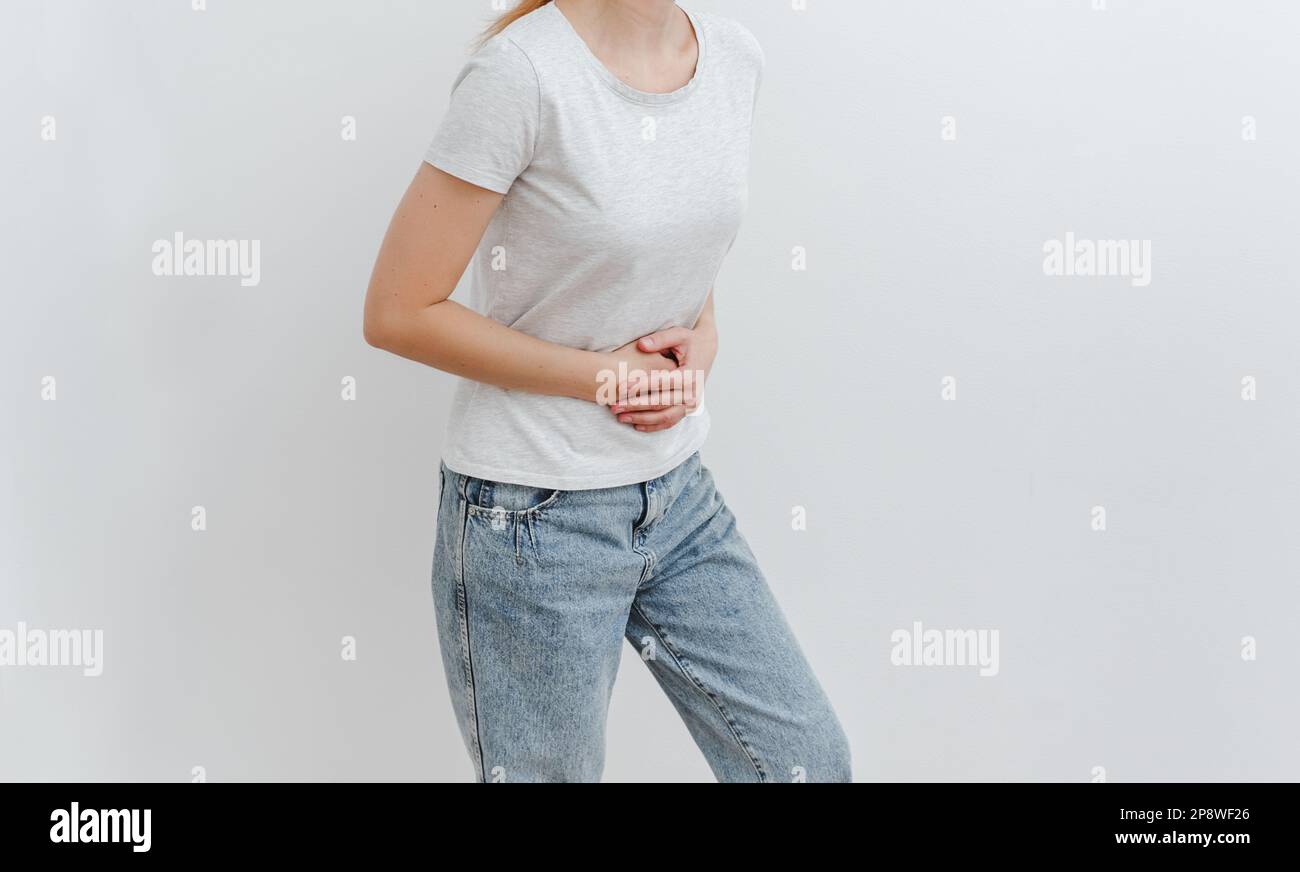 A young woman holds on to her stomach in pain. Digestive problems ...