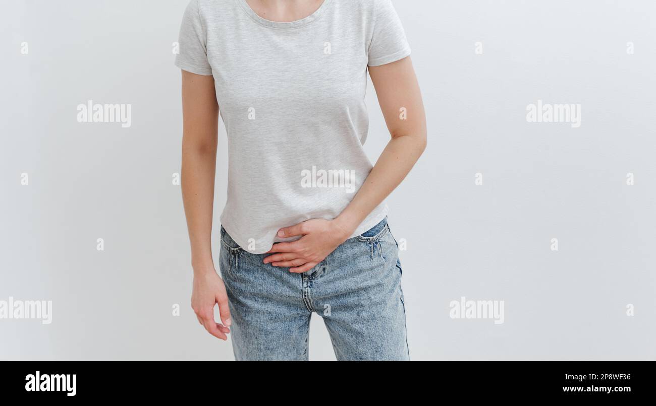 A young woman holds on to her stomach in pain. Digestive problems ...