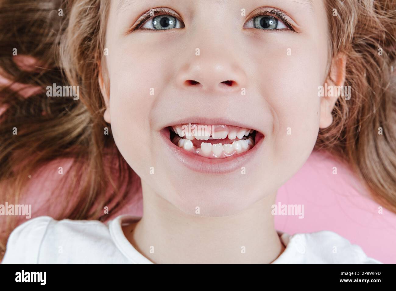Happy smiling child portrait on the pink background. Close-up of teeth ...