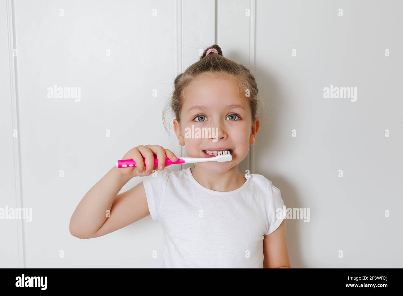 A child brushes his teeth with a pink toothbrush. White background ...