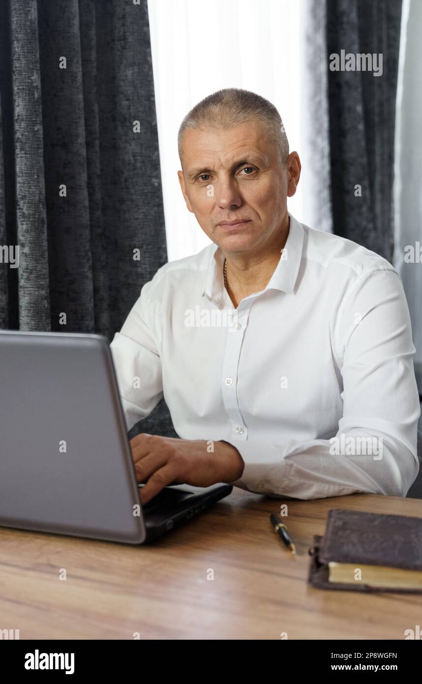 Portrait of middle aged business man working at home with laptop ...