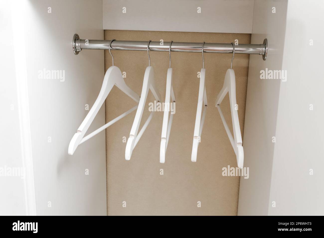 White empty wardrobe closet with hangers. Wooden white hangers on a rod ...