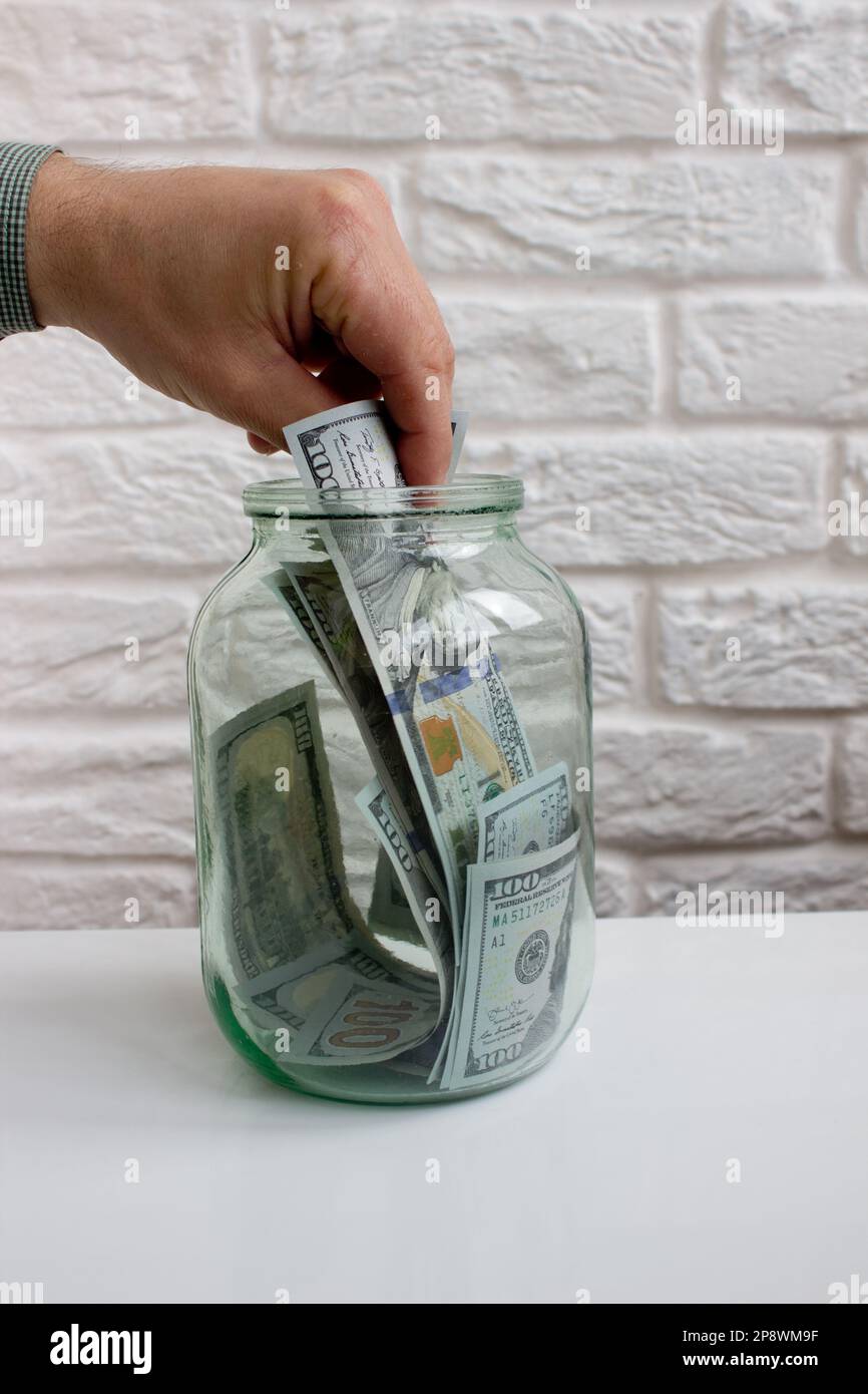 Mens hand taking out paper dollar banknote from glass jar Stock Photo ...