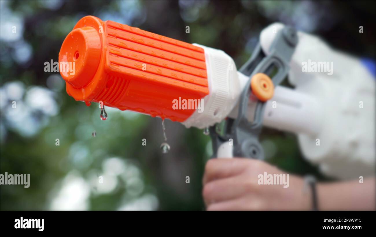 Water gun spraying water close up outside. Plastic Toy Weapon splashing ...