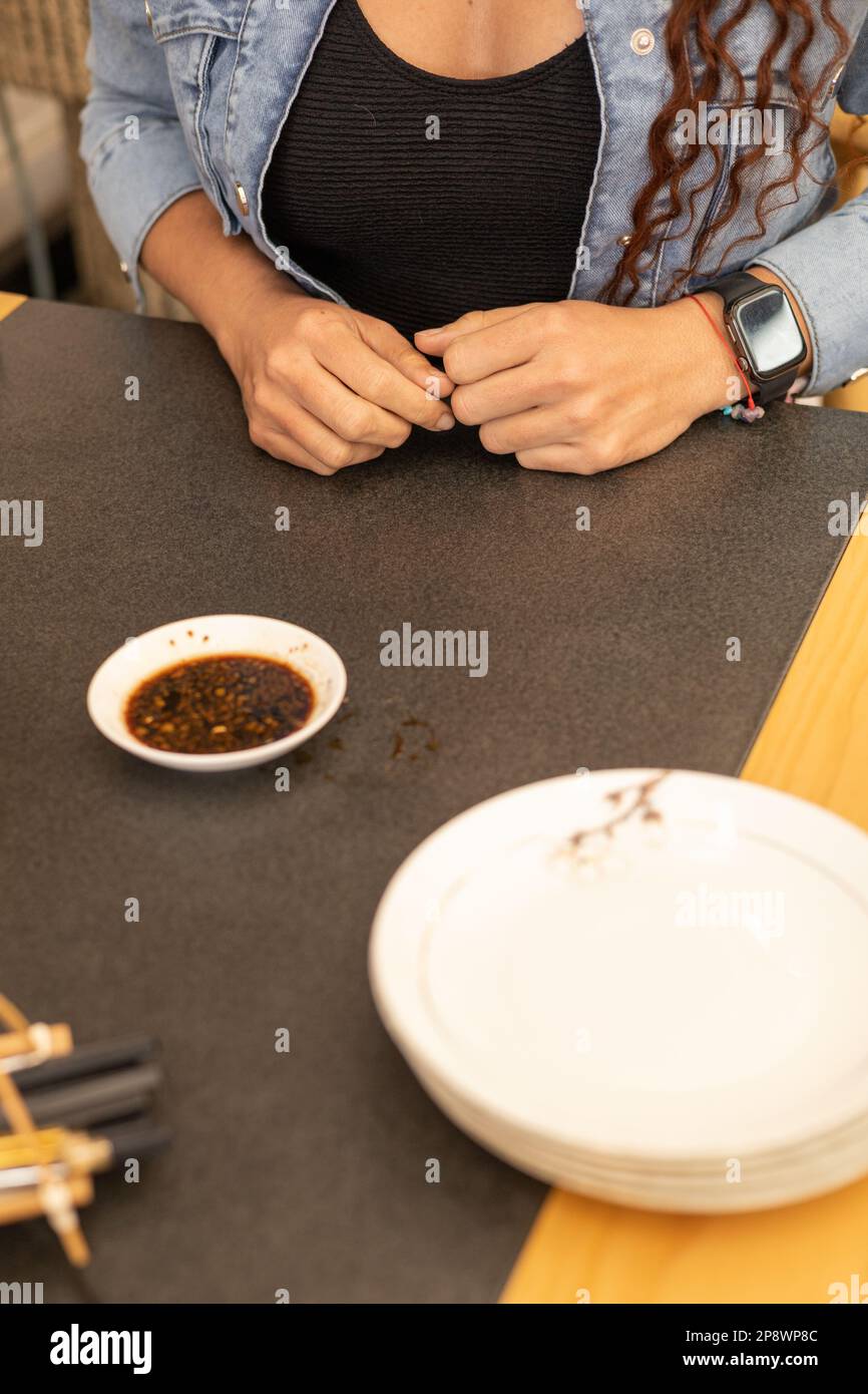 restaurant table with empty plates and a sauce, hands of a person ...