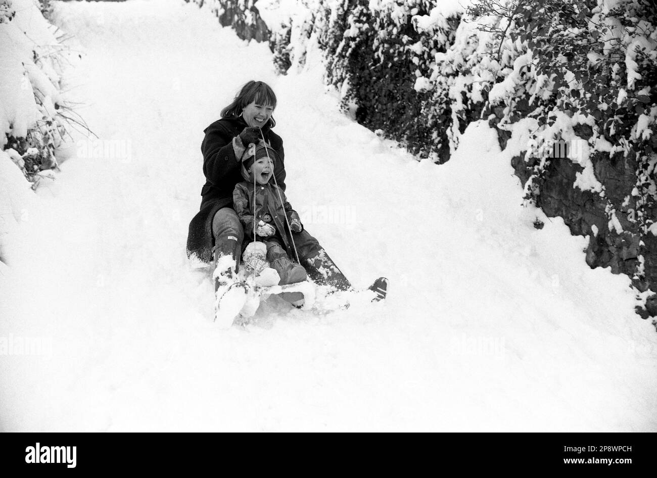 Mother and child sledging in deep winter snow Britain 1980 Stock Photo ...