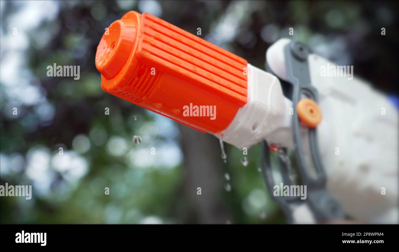 Water gun spraying water close up outside. Plastic Toy Weapon splashing ...