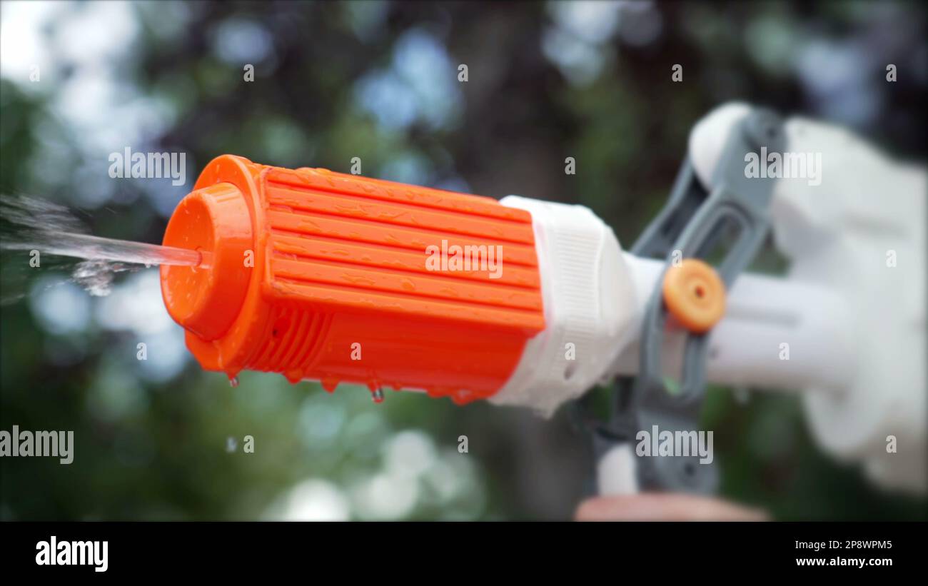 Water gun spraying water close up outside. Plastic Toy Weapon splashing ...