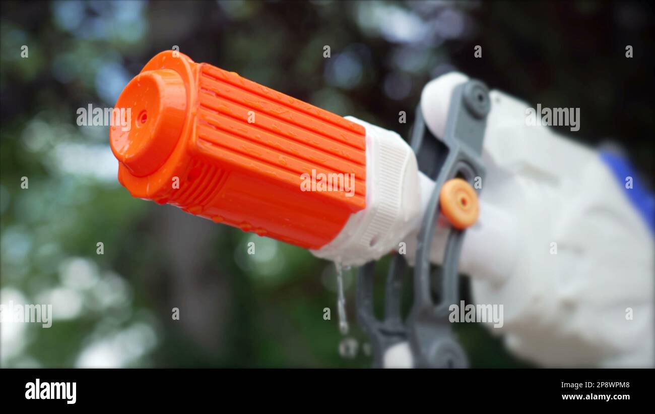 Water gun spraying water close up outside. Plastic Toy Weapon splashing ...