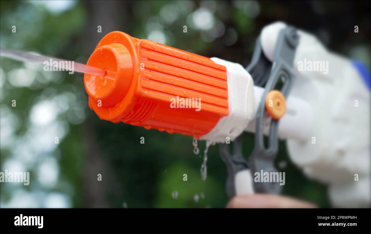 Water gun spraying water close up outside. Plastic Toy Weapon splashing ...