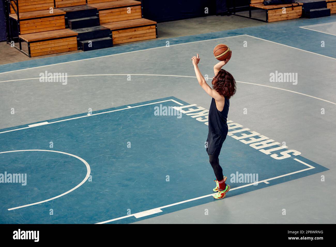 Sports guy on the basketball court, a guy with long hair trains with ...