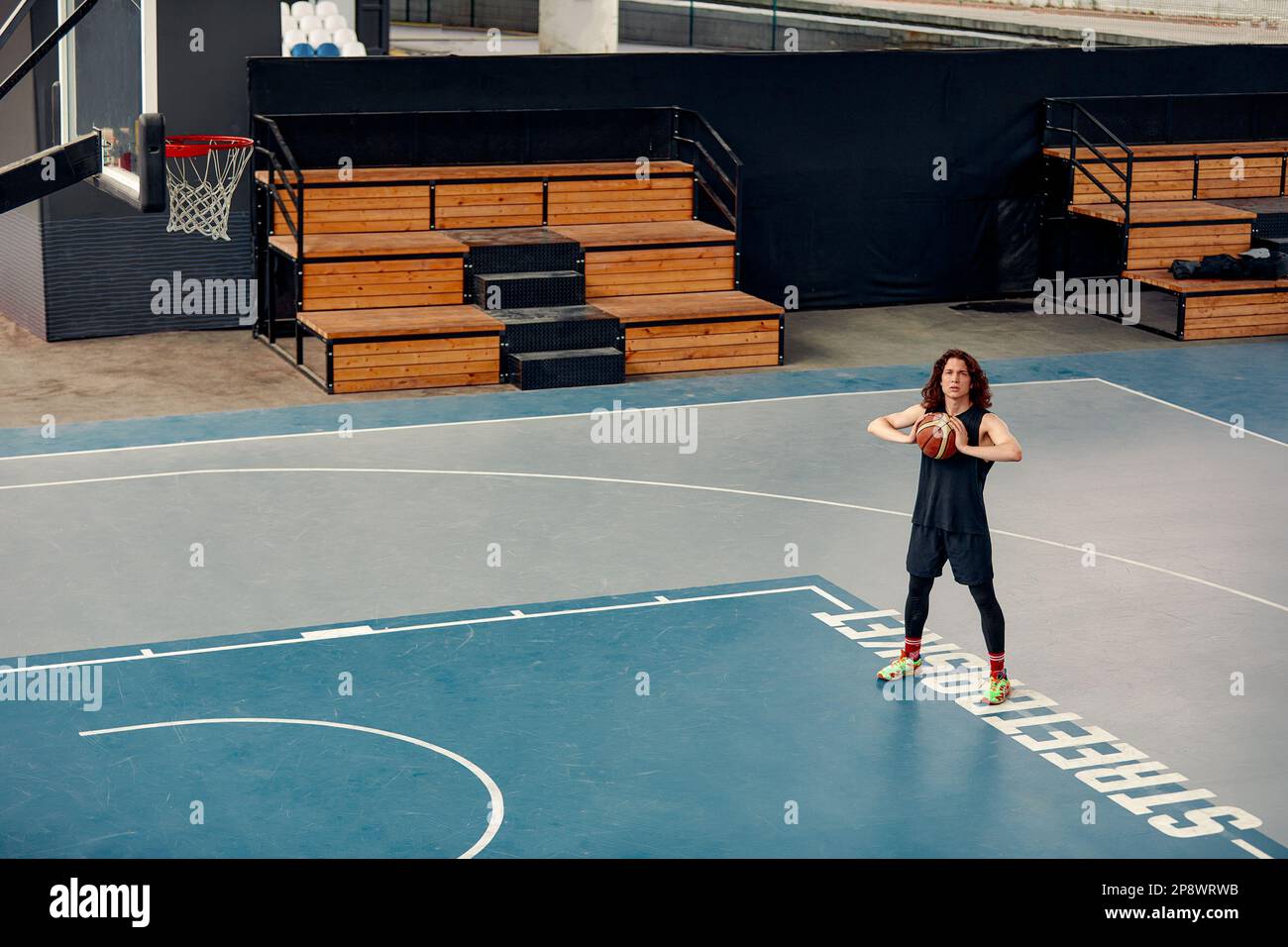 Sports guy on the basketball court, a guy with long hair trains with ...
