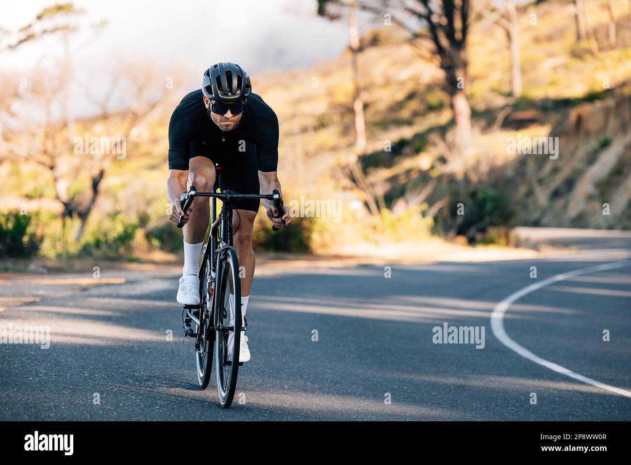 Professional cyclist in black sports attire going down a hill. Cyclist ...