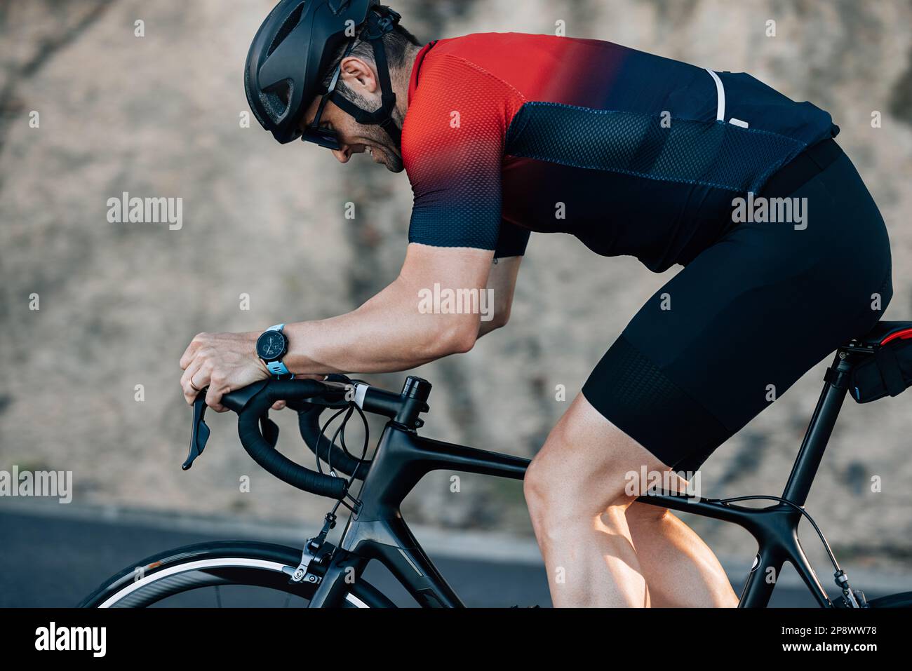 Close-up of a male professional cyclist riding a road bike. Young man ...