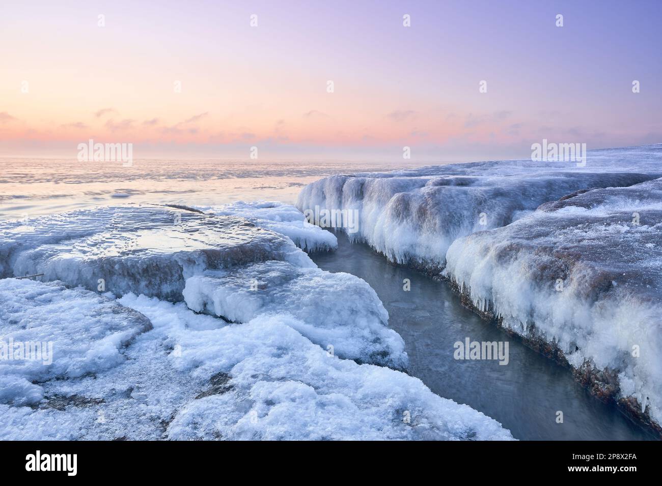 An idyllic frozen rocky shore with pink sky on the horizon, perfect for ...