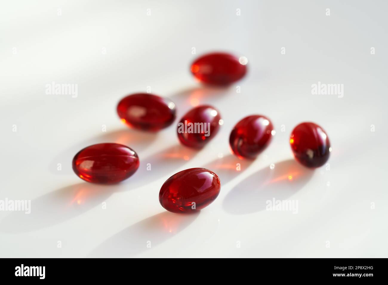 Closeup of red krill oil globules on white background Stock Photo - Alamy