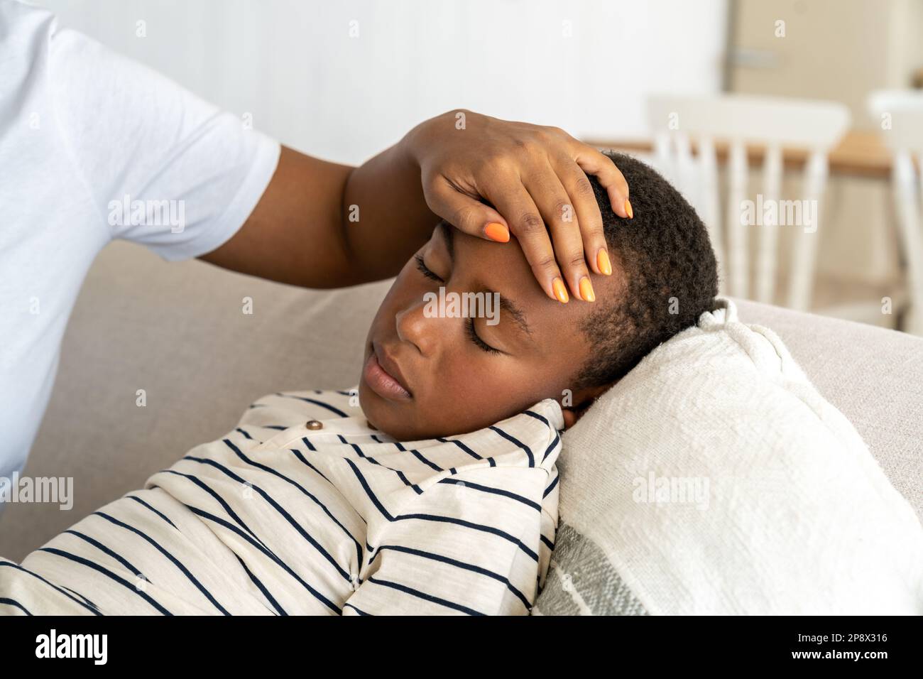 Sick unhealthy black child small boy lies with closed eyes near mom ...