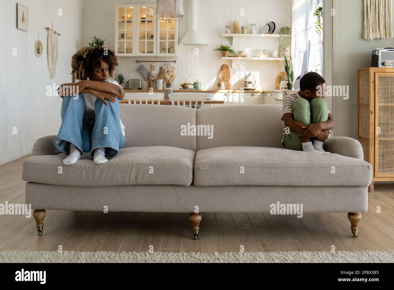 Offended mom and son sit on opposite sides of couch pout at each other ...