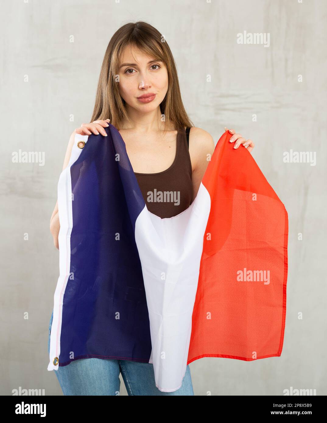 Sad young woman holding flag of France against unicoloured background ...