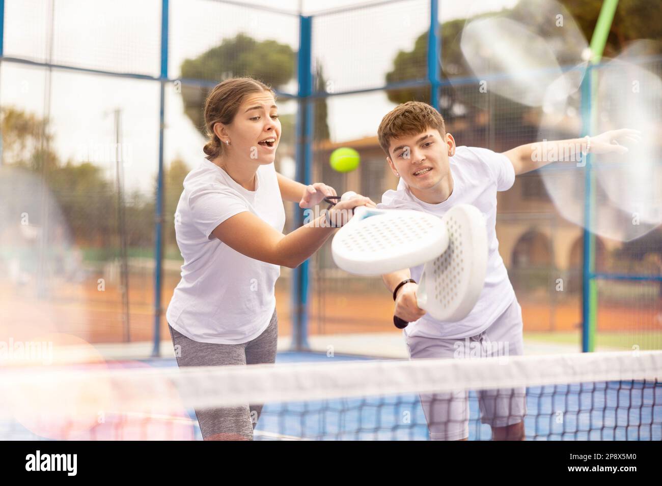 Emotional male and female tennis partners hitting ball with rackets on ...