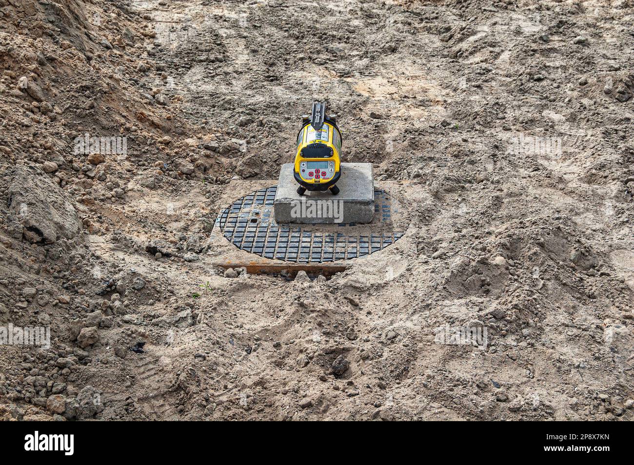electronic surveyor placed on a square terrace tile on a sandy terrain ...