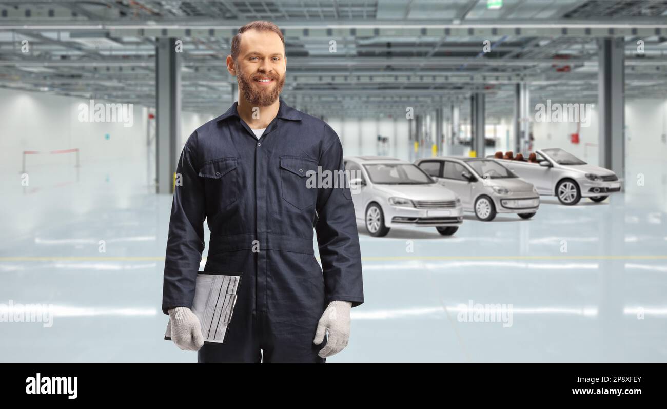 Car mechanic in a uniform holding a clipboard inside a factory Stock ...
