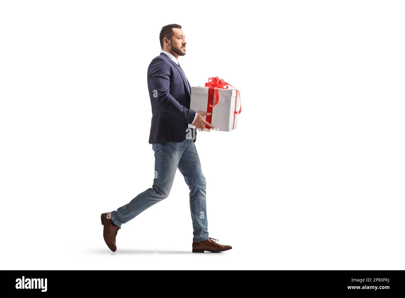 Full length profile shot of a young man walking with a gift box ...
