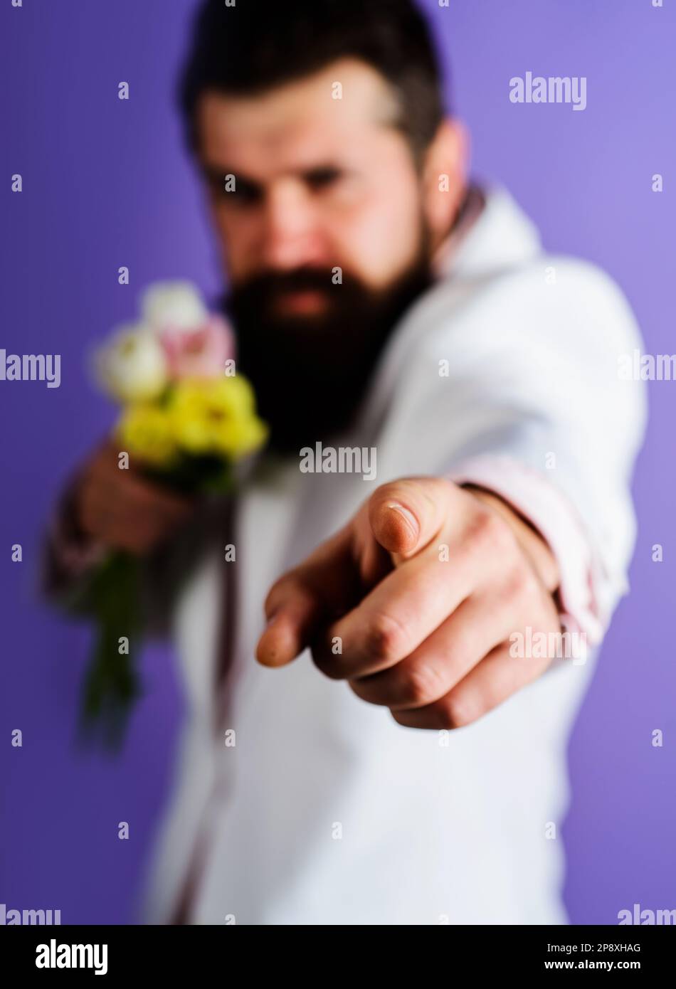 Bearded man with flowers bouquet pointing finger forward. Selective ...
