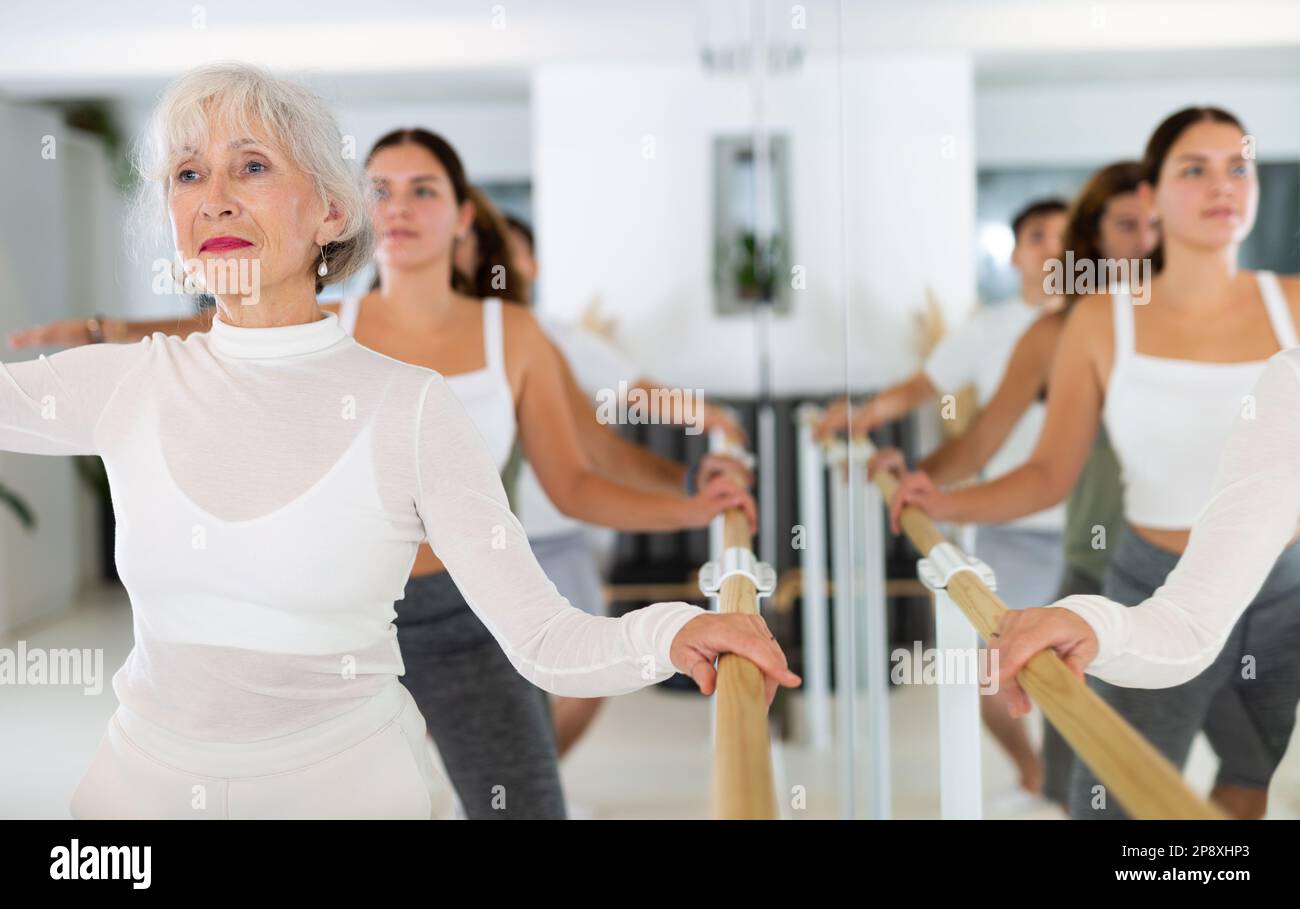 Senior woman and group of adult dancers practice ballet moves in ...