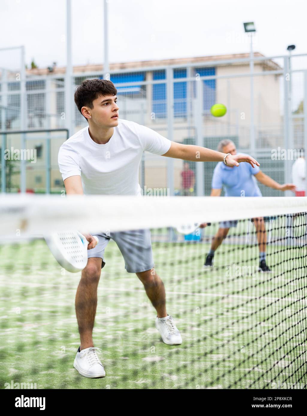 Sporty young guy playing padel on open court Stock Photo - Alamy