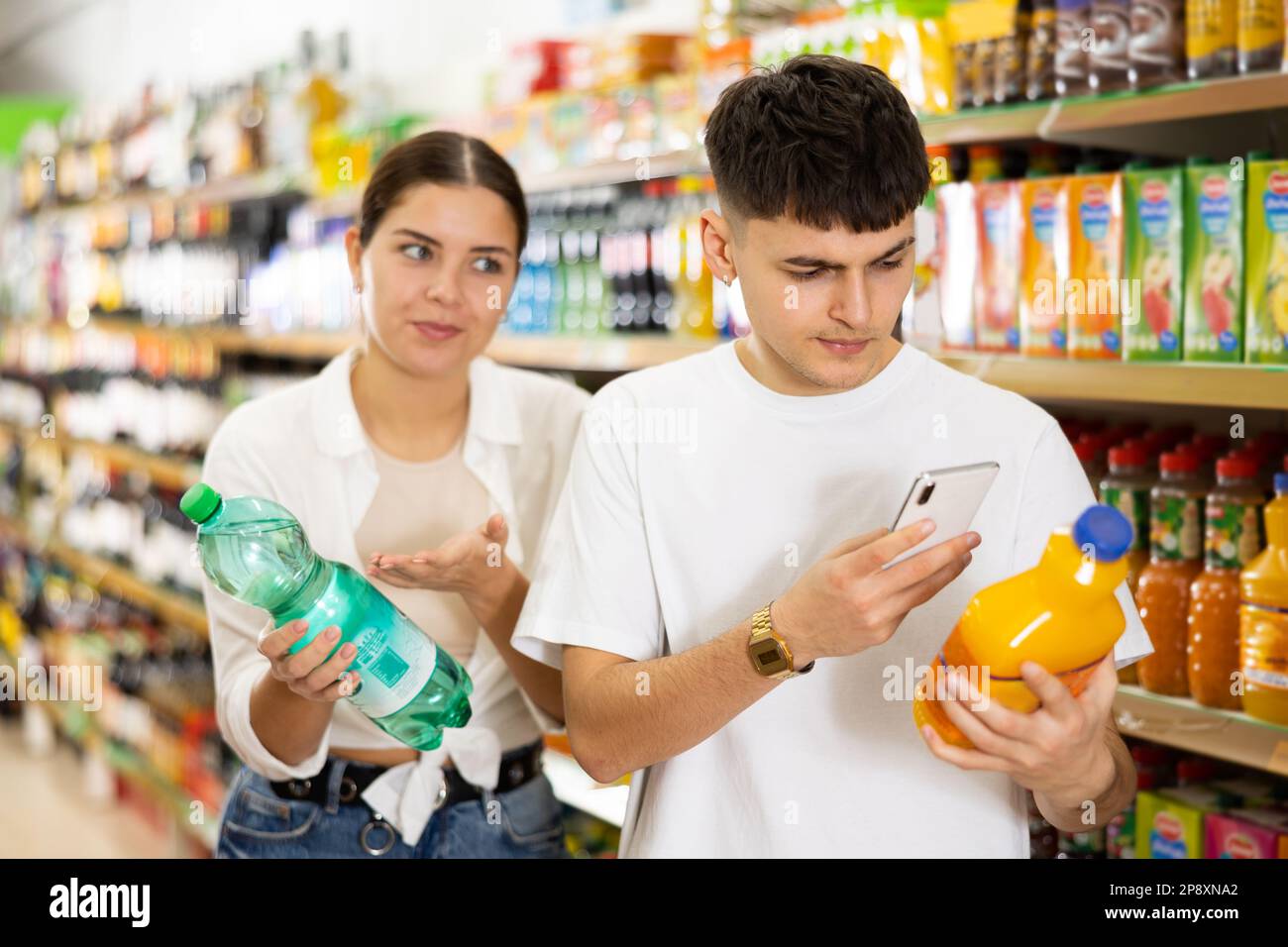 Couple scanning barcodes on bottles of beverages with phone in ...
