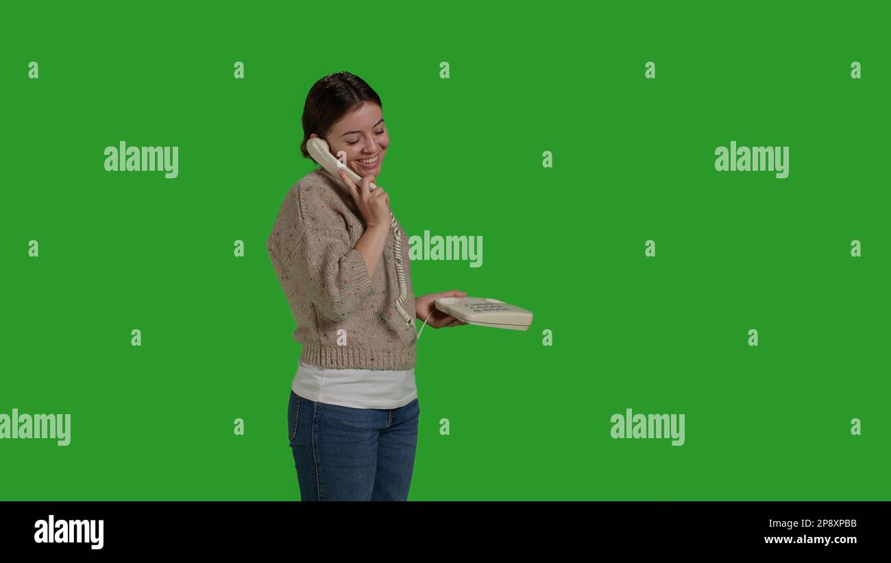 Side view of joyful girl chatting on landline phone call, using ...