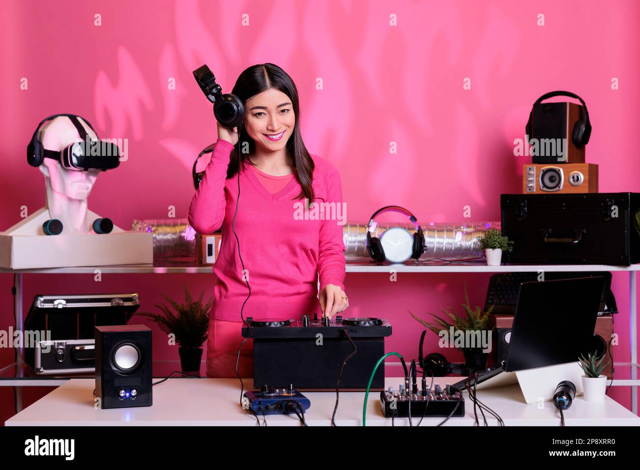 Asian performer standing at dj table while playing electronic song ...