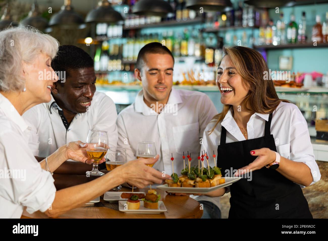 Positive waiter holding tray with pinchos at restaurant Stock Photo - Alamy