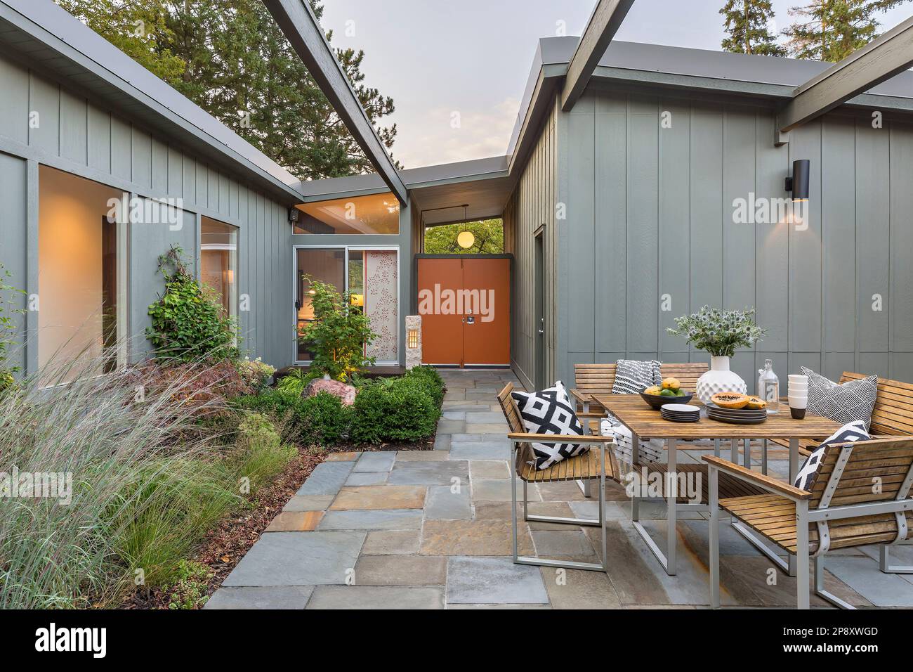 Dining table and chairs in garden courtyard of mid-century modern house ...