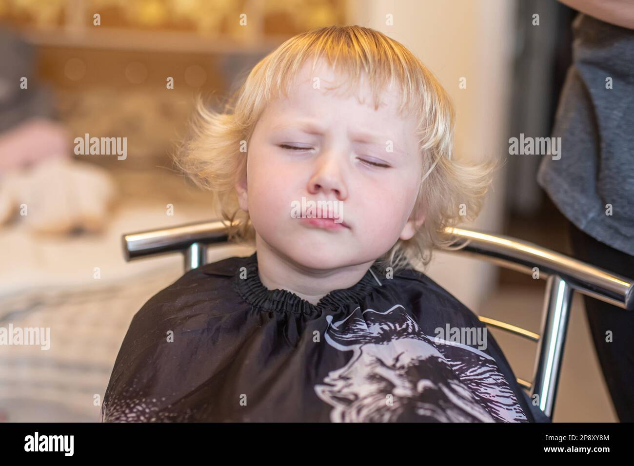A little girl in a beauty salon closed her eyes after a haircut with a ...