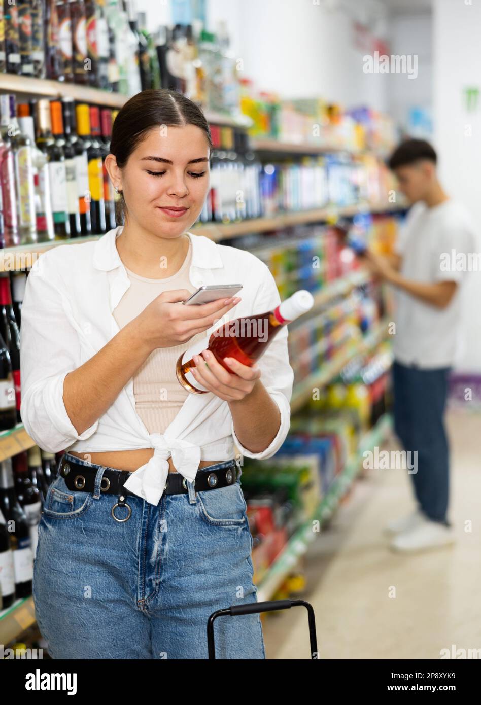 Young woman scanning barcode on wine bottle with smartphone Stock Photo ...