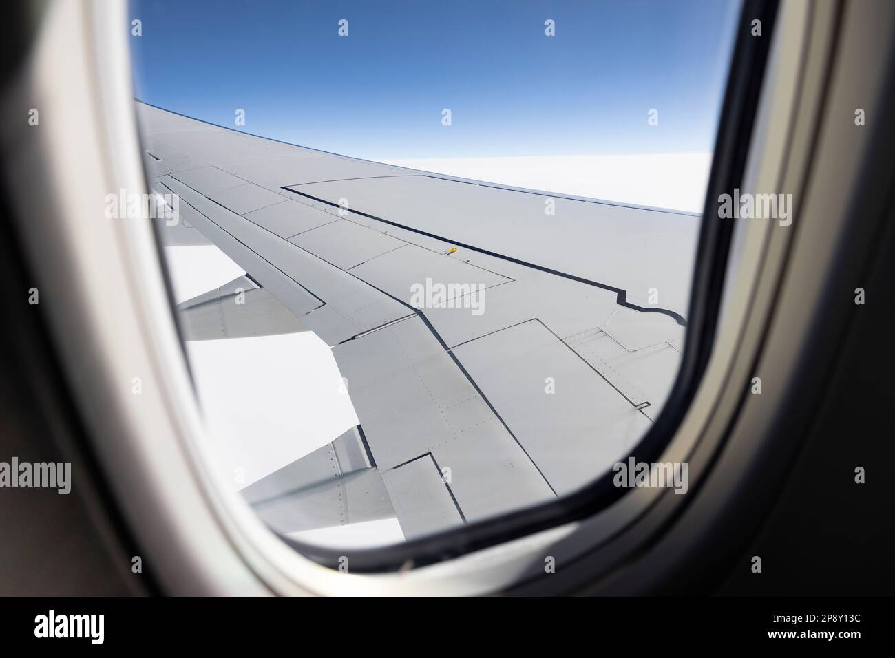 Looking through an airborne passenger jet window at portion of wing ...