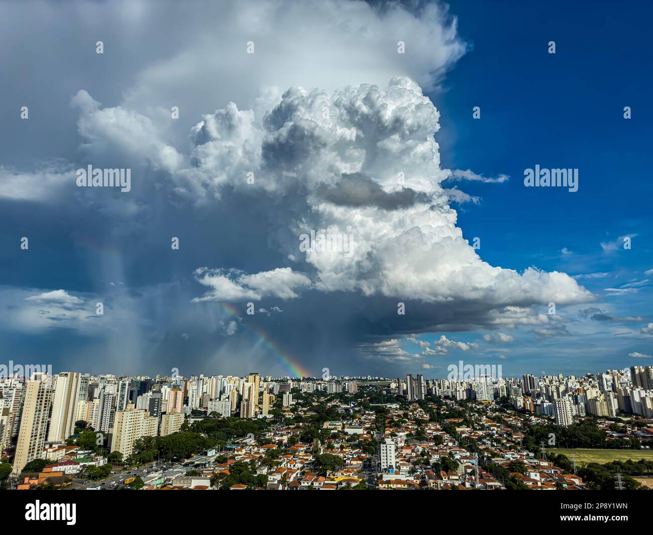 Beautiful rain cloud with a rainbow in the city Stock Photo - Alamy