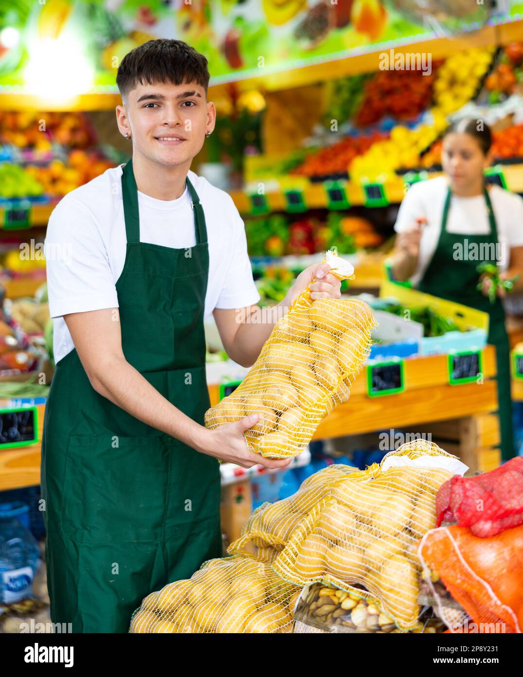 Male shop assistant lays potatoes on counter in grocery shop Stock ...