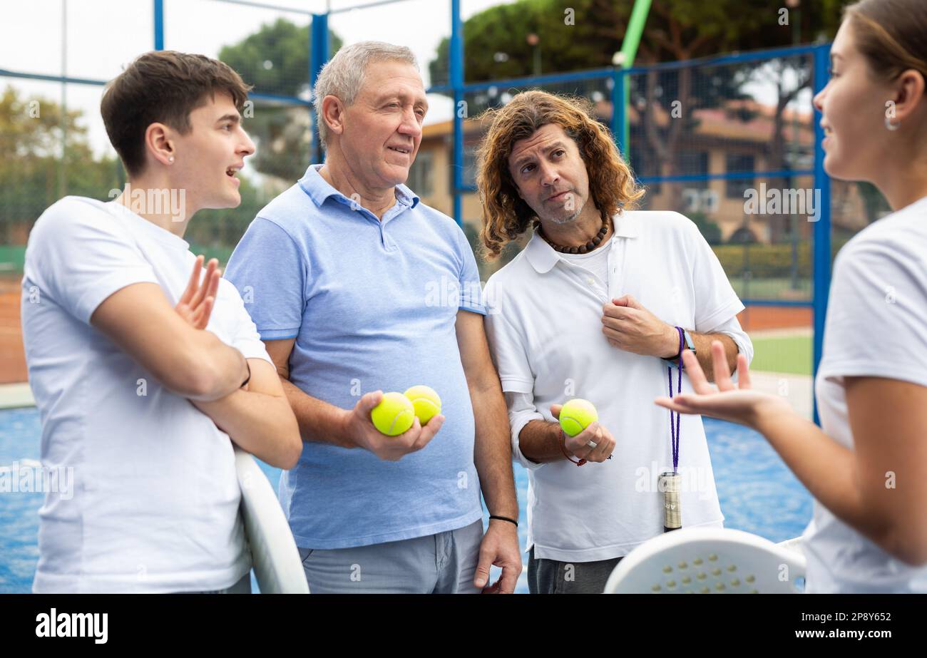 Group portrait of four padel players of different ages standing at ...