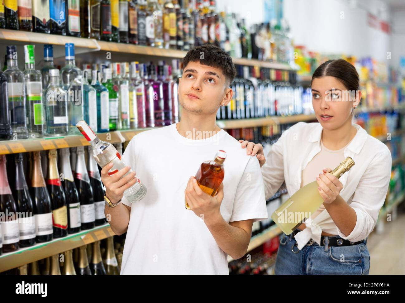 Man and woman choose high-quality alcoholic drink in supermarket Stock ...