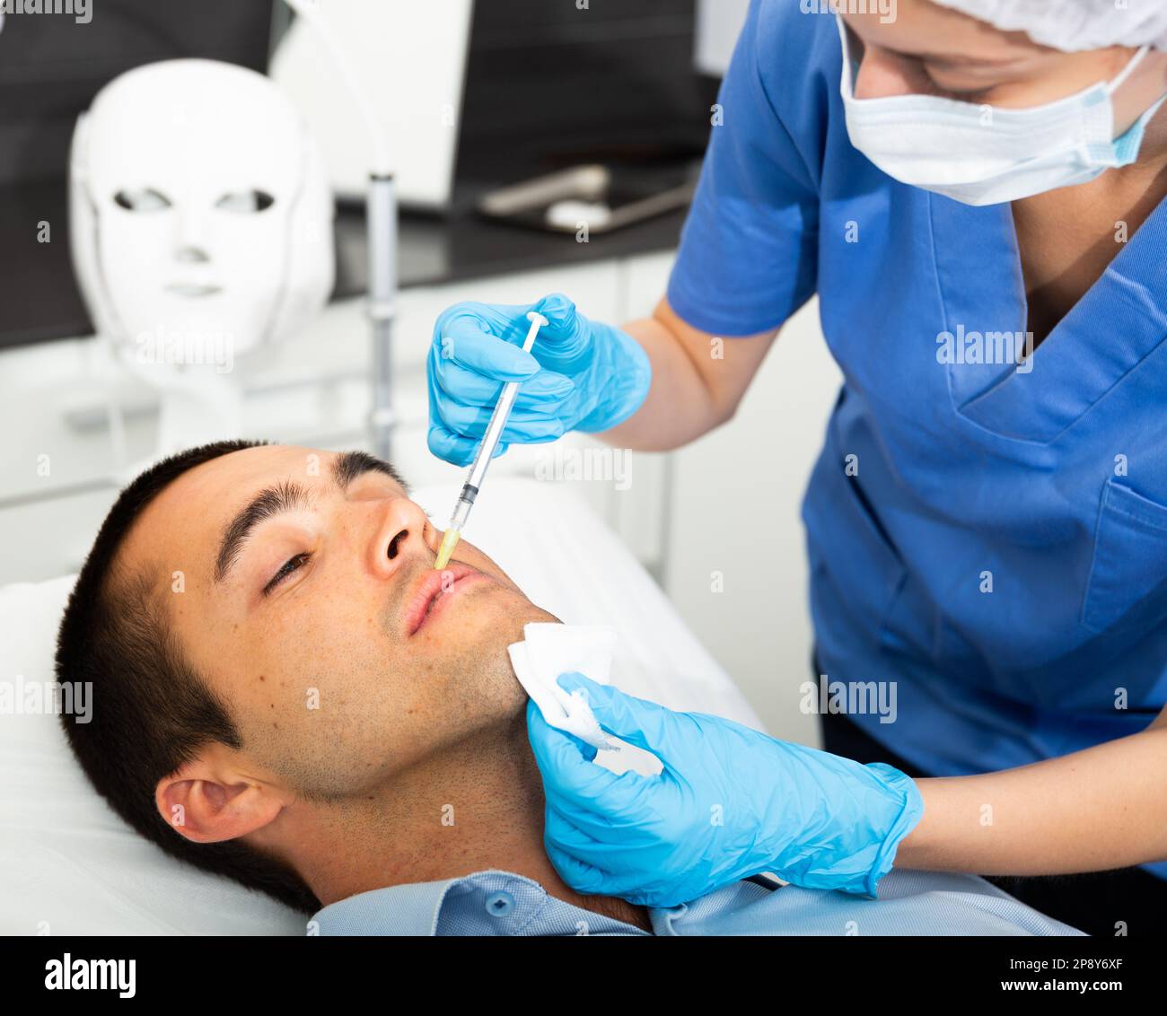 Man receiving injections for facial contouring in cosmetology clinic ...